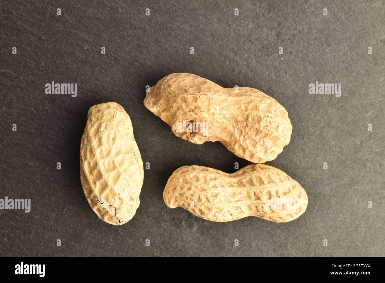 Organic ripe unpeeled peanuts, close-up, on a slate serving board, top ...