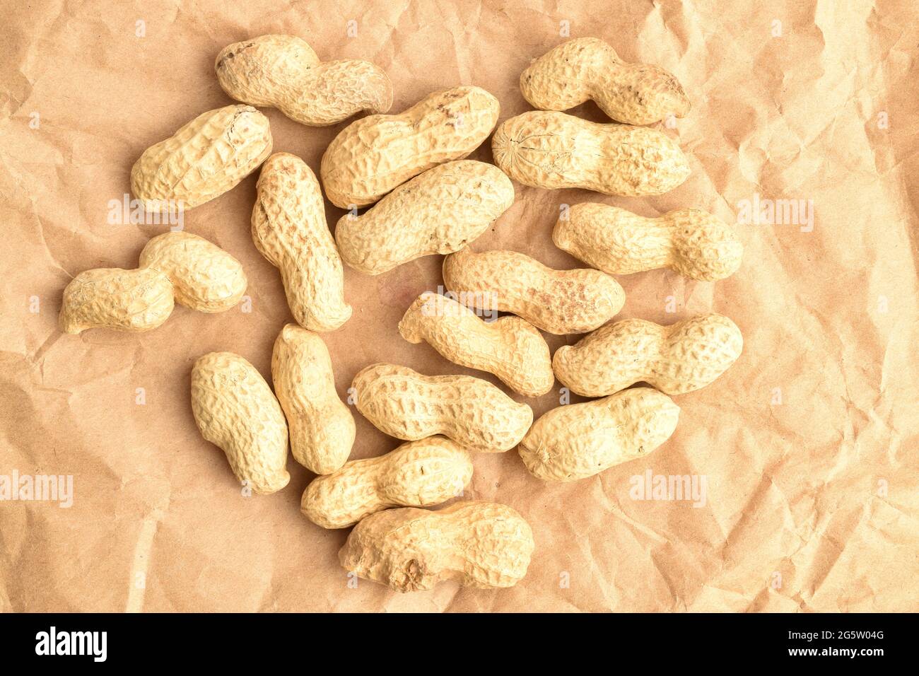 Organic ripe unpeeled peanuts, close-up, on brown paper, top view Stock ...