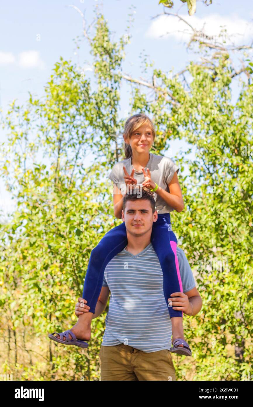 Defocused brother giving sister ride on back. Portrait of happy girl on ...