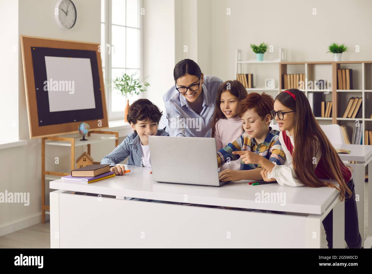 Elementary school kids and female teacher in school classroom working ...