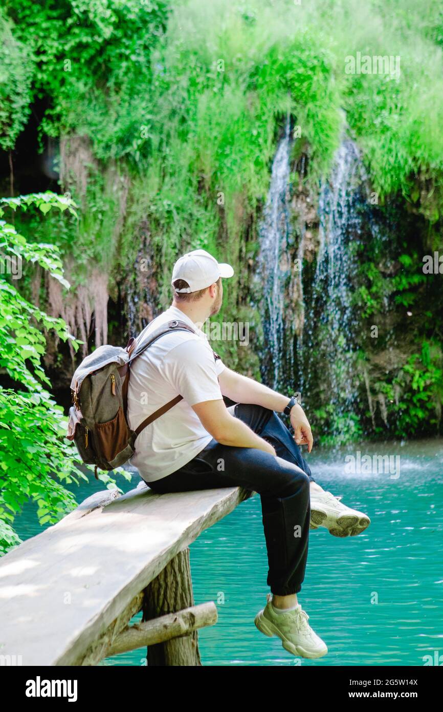 man hiker backpacker looking at waterfall with blue lake copy space ...