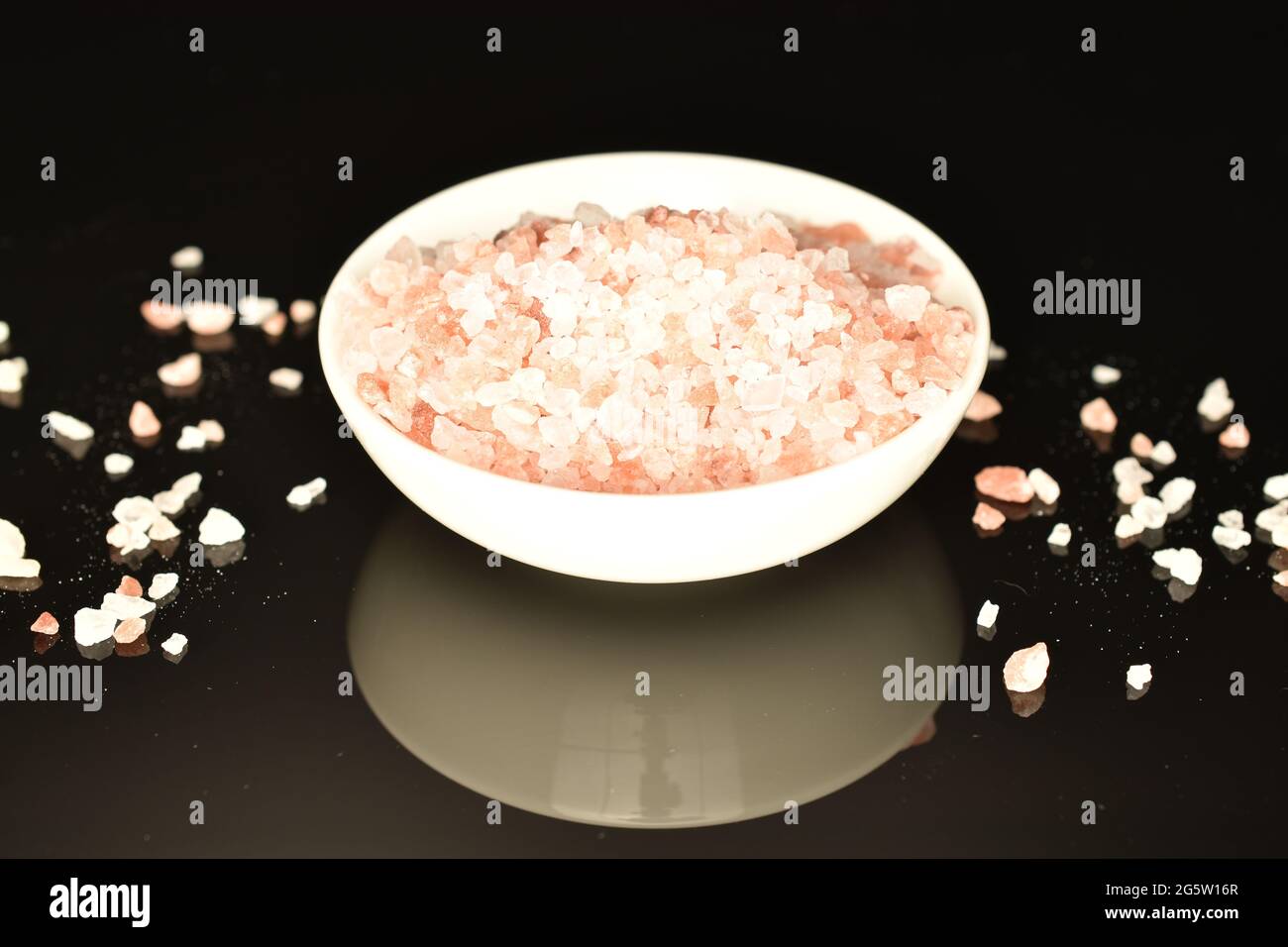 Rock salt of pink color in a white salt shaker, close-up, isolated on ...