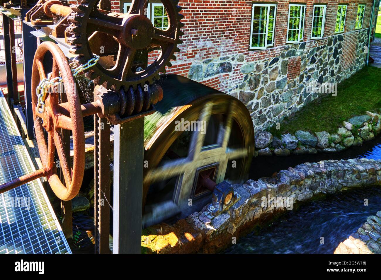 Wooden mill wheel of a historical water mill turns in the flowing water ...