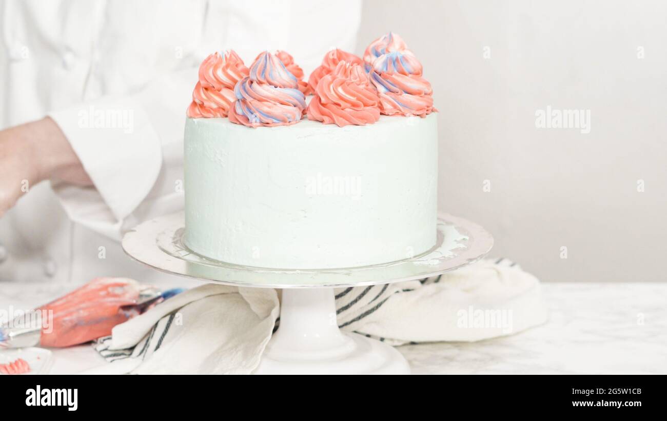 Piping buttercream rosettes on top of round three-layer vanilla cake ...