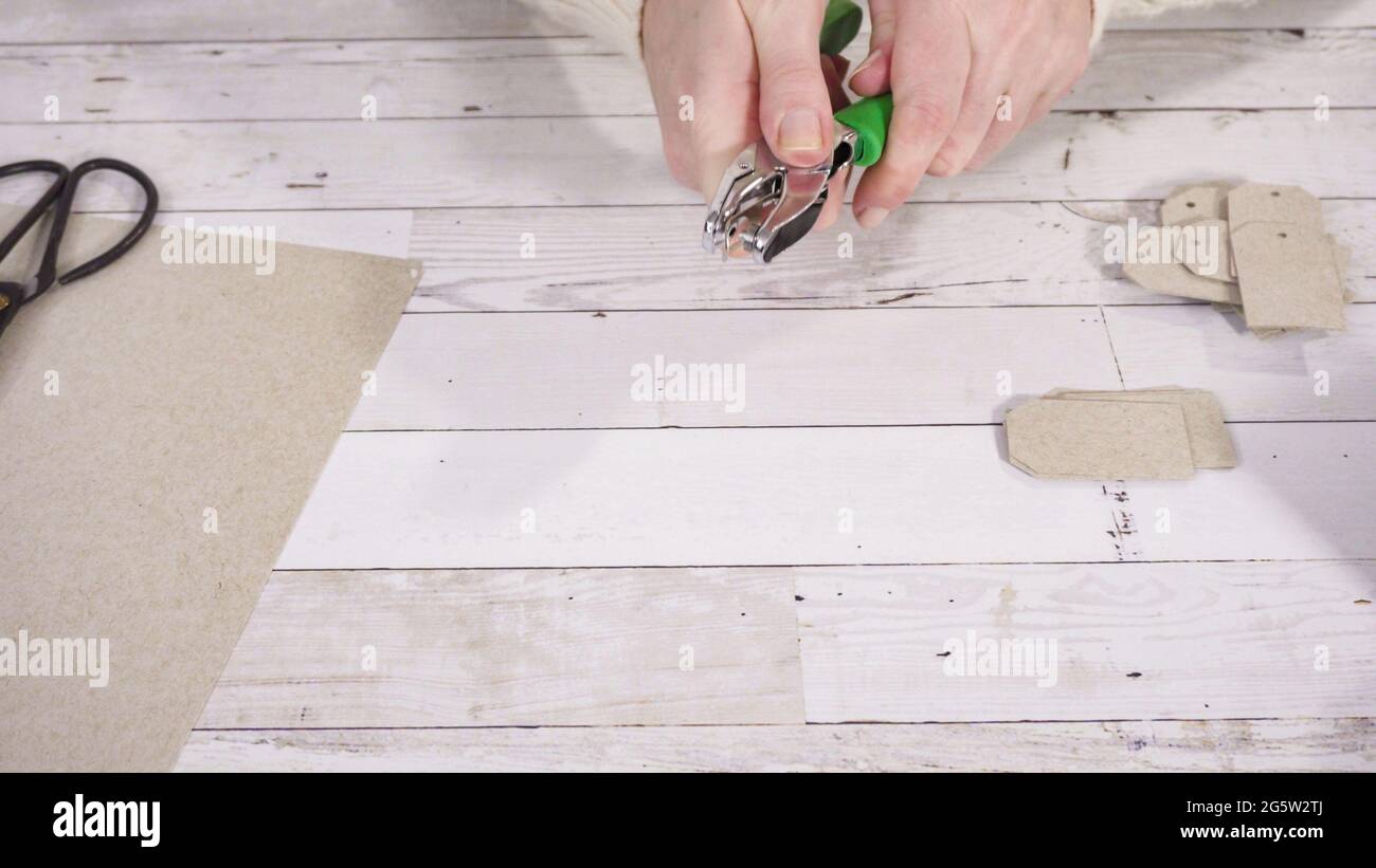 Step by step. Cutting out gift tags from brown paper with a paper punch ...