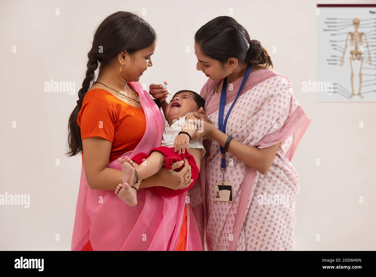 A health officer giving polio drops to a baby in his mother's lap Stock ...