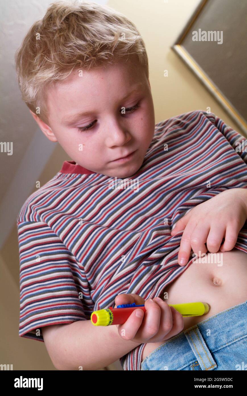 young boy self injecting insulin with an insulin pen into his abdomen ...
