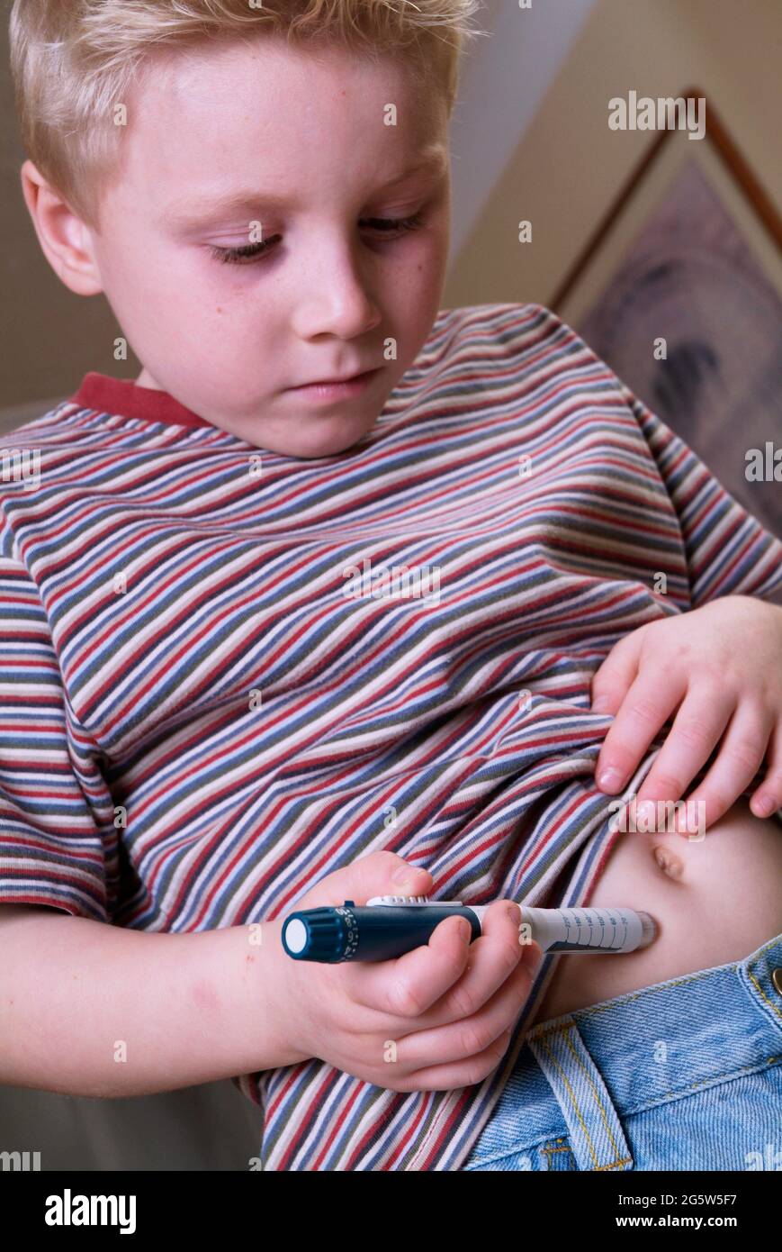 young boy self injecting insulin with an insulin pen into his abdomen ...