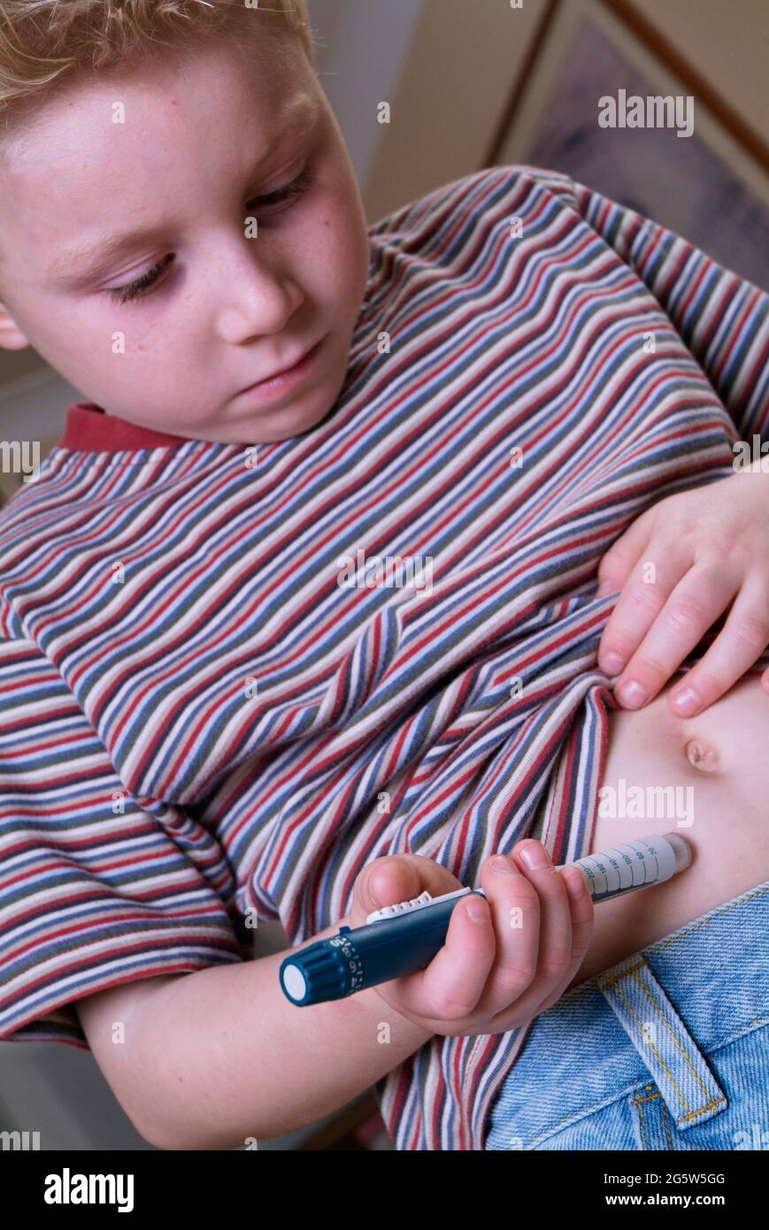 young boy self injecting insulin with an insulin pen into his abdomen ...