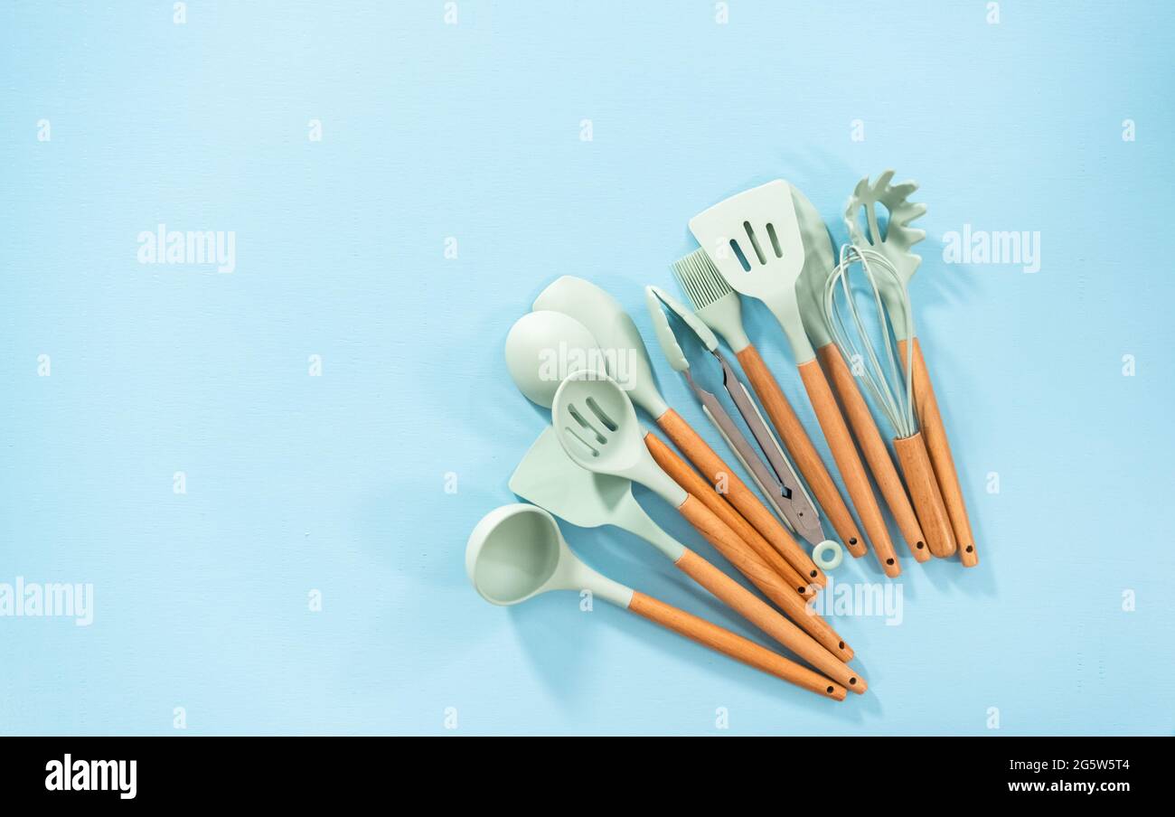 Flat lay. New blue silicone kitchen utensils with wooden handles on a ...