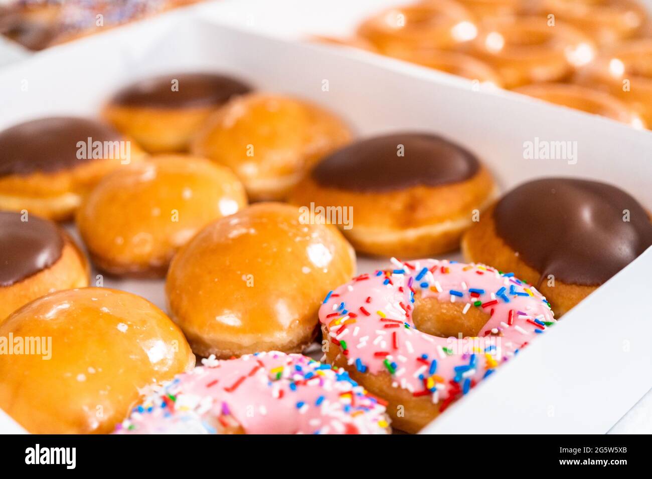 Variety of store-bought doughnuts in a white paper box Stock Photo - Alamy