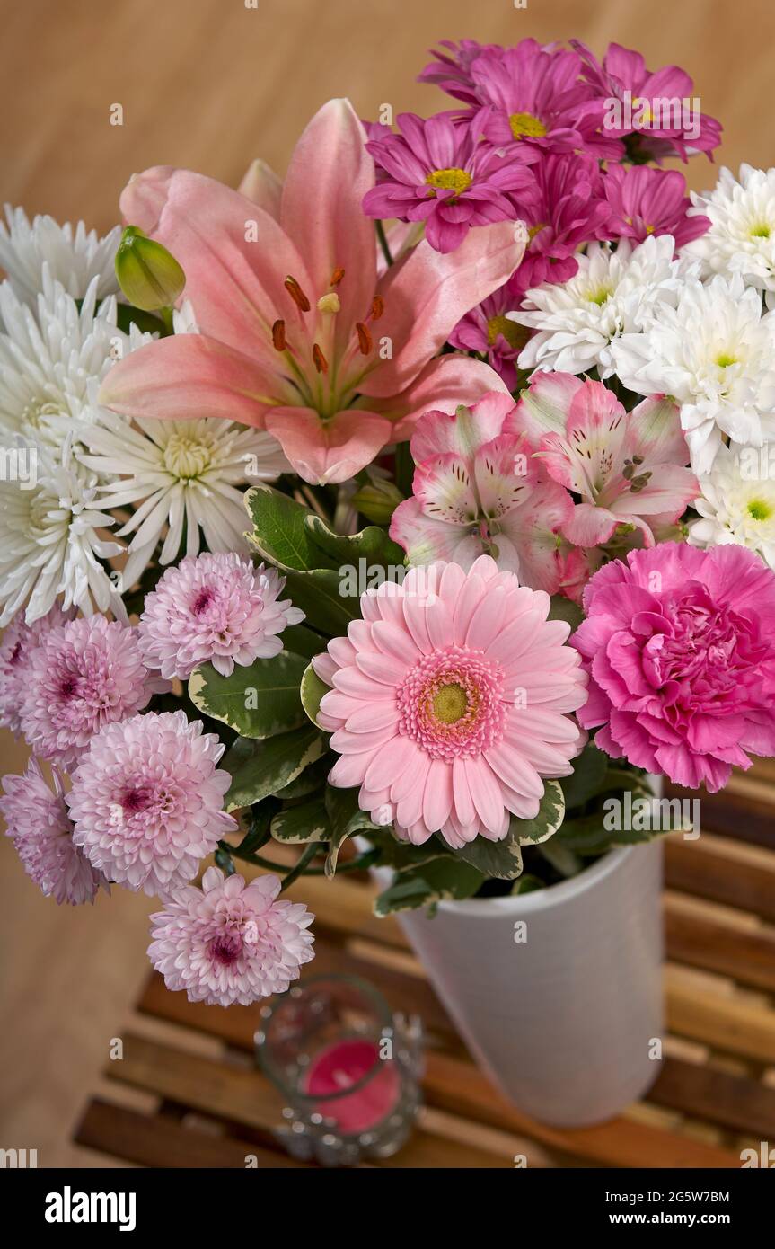 A cropped photograph of a vase of fresh cut flowers on table indoors in ...