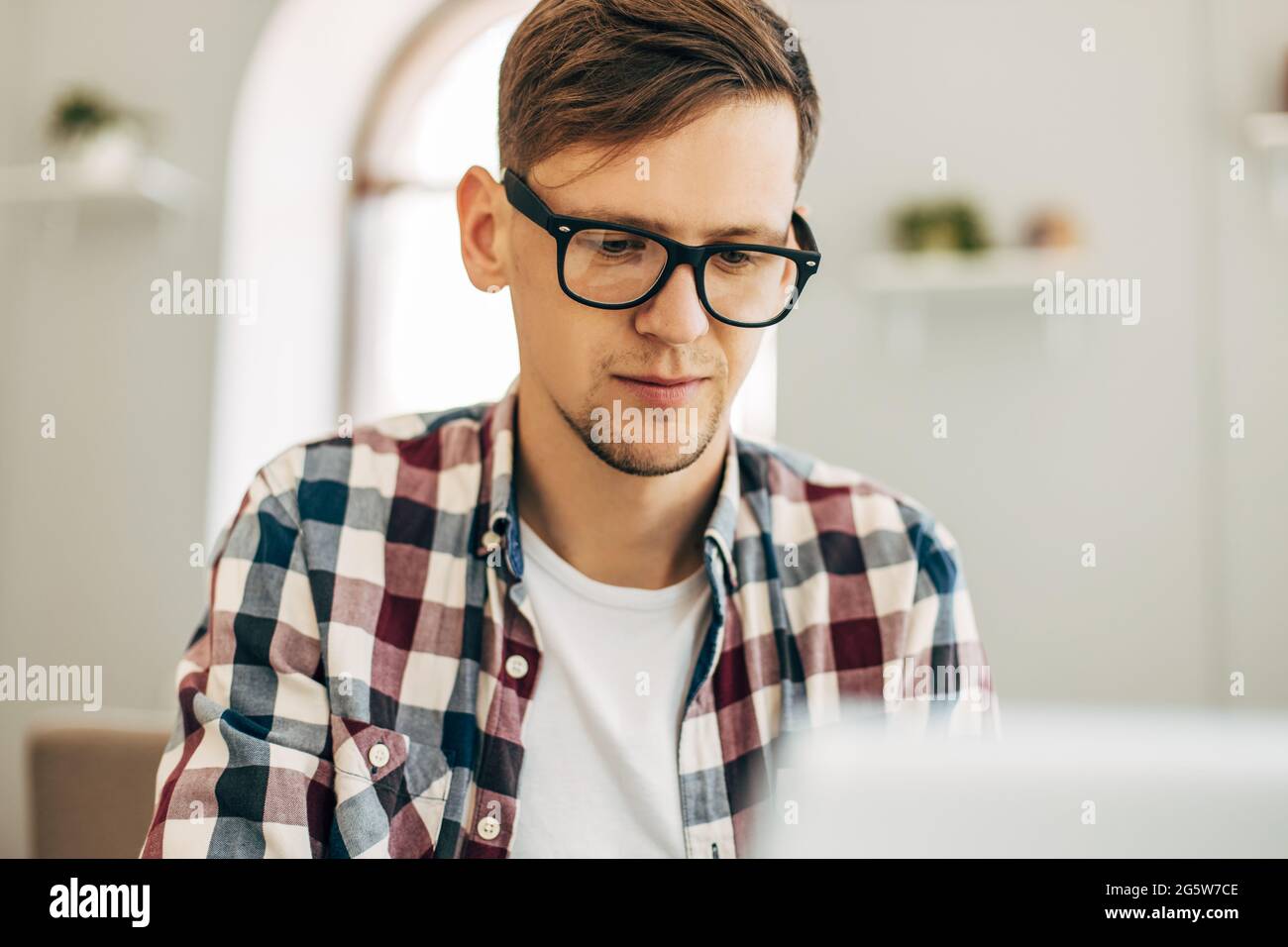 Young smiling business man, uses laptop, man works on the internet ...