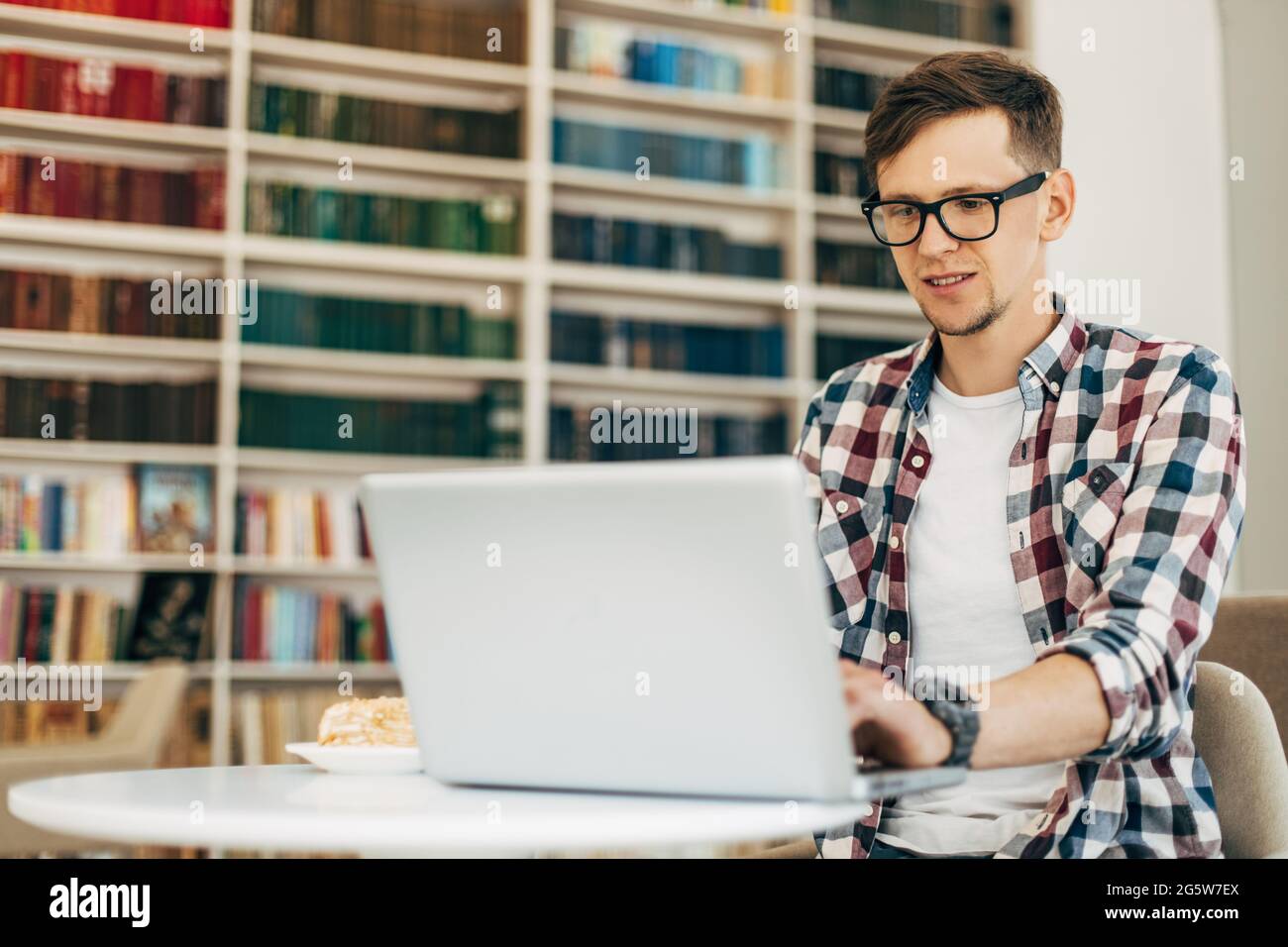 Young smiling business man, uses laptop, man works on the internet ...