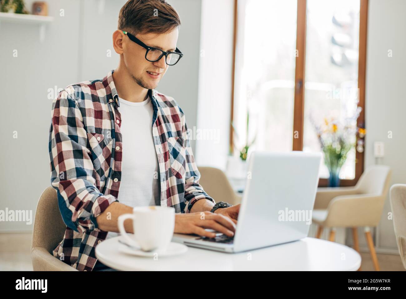 Happy young stylish man wearing glasses, uses laptop for video call on ...