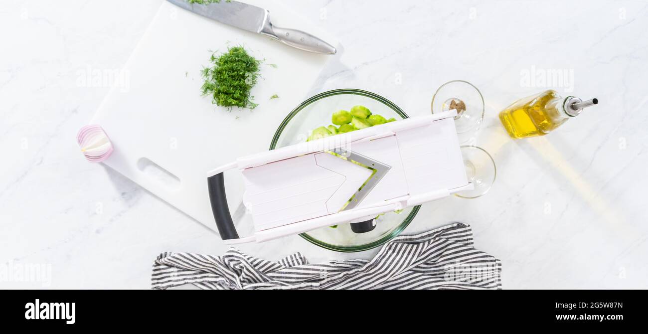 Flat lay. Slicing vegetables on slicer to make summer cucumber salad ...