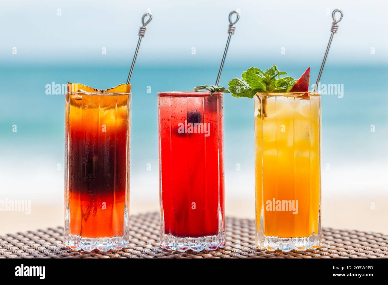 Set Of Refreshing Fruit Cocktails Standing On Table On Beach Near