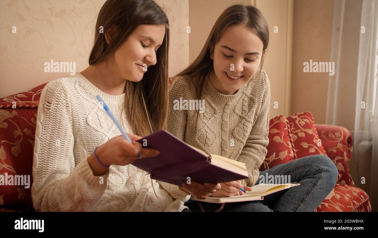 Happy smiling teenage girls laughing and smiling while doing homework ...