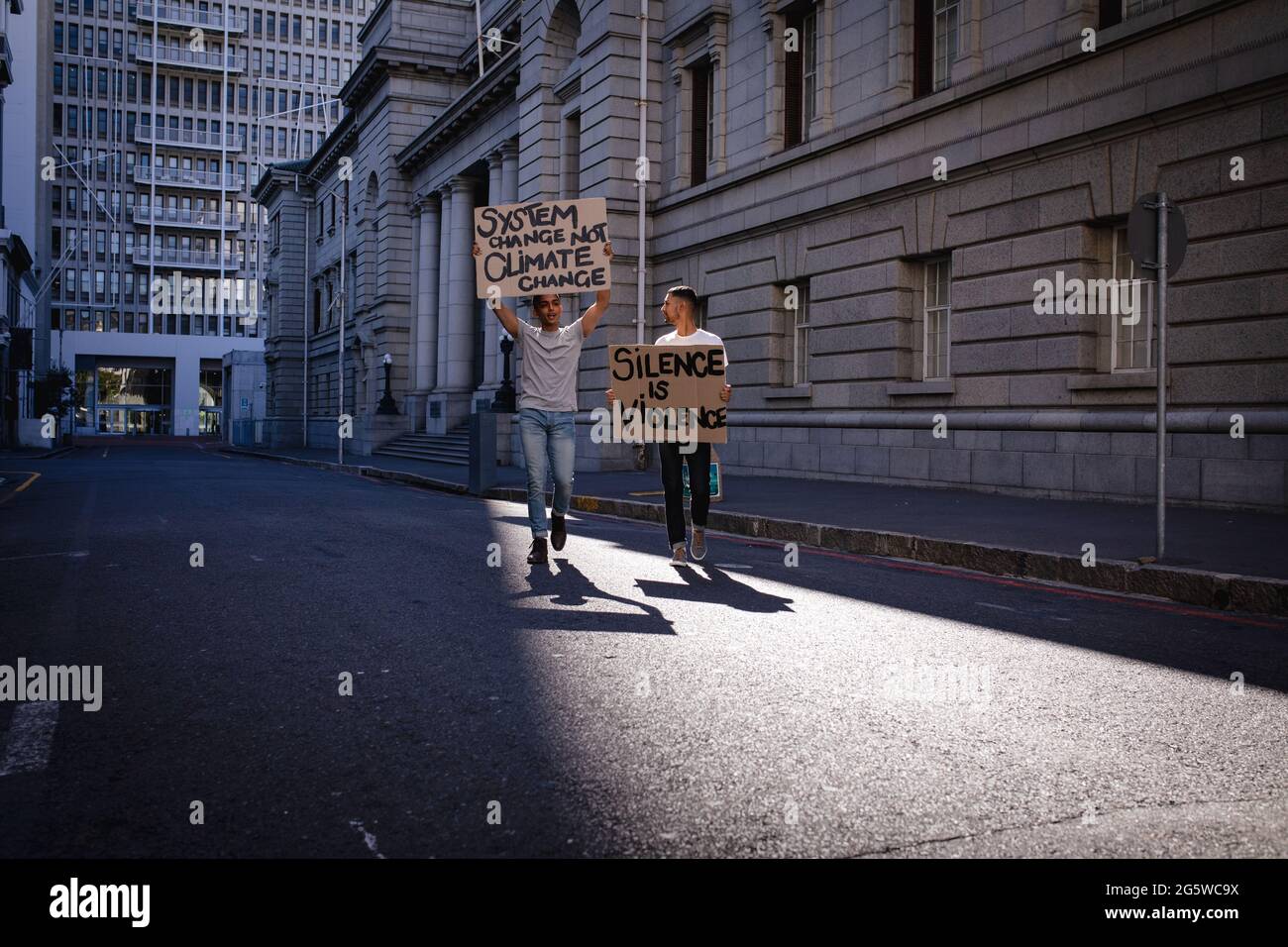 Two mixed race male friends carrying hand painted protest signs walking ...