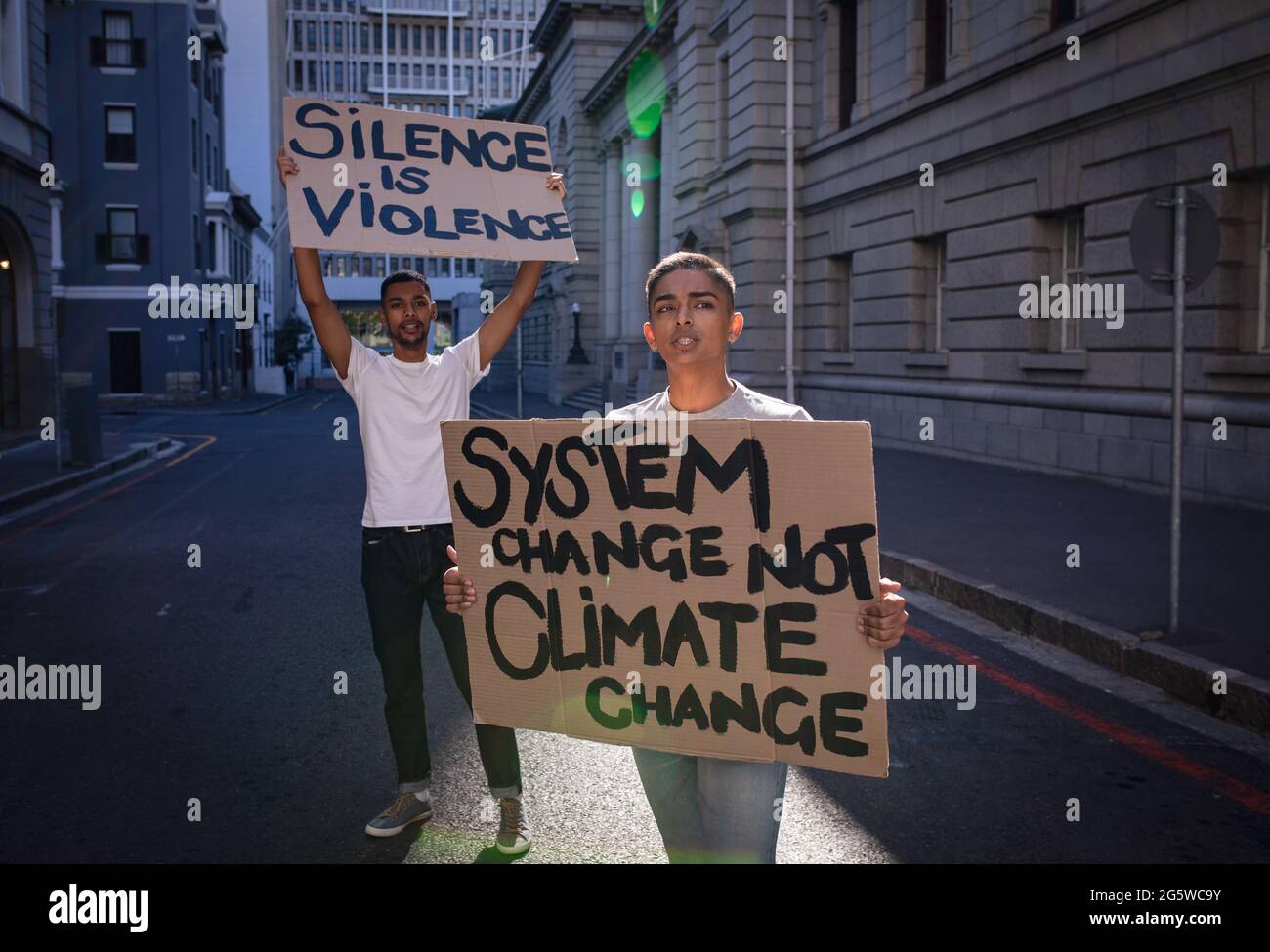 Two mixed race male friends carrying hand painted protest signs with ...