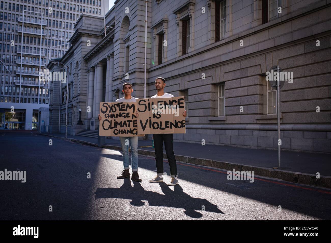 Two mixed race male friends carrying hand painted protest signs walking ...