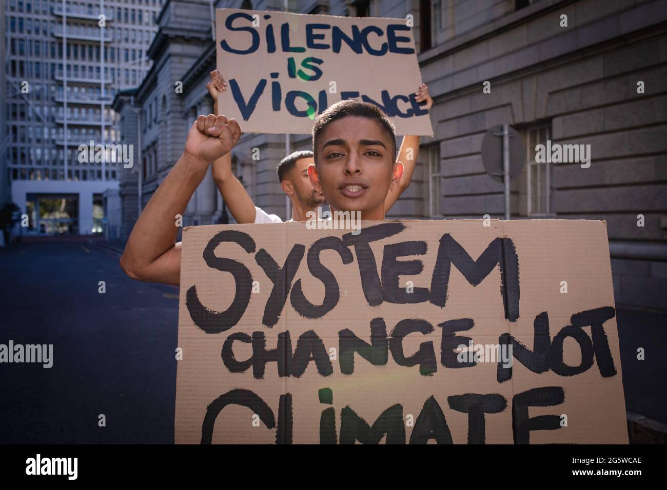 Two mixed race male friends carrying protest signs with slogans, one ...