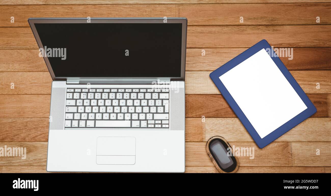 Overhead view of laptop, mouse and digital tablet on wooden surface ...