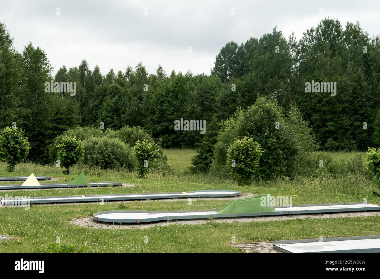 Mini golf court. Summer outdoor game. Green field and trees on ...