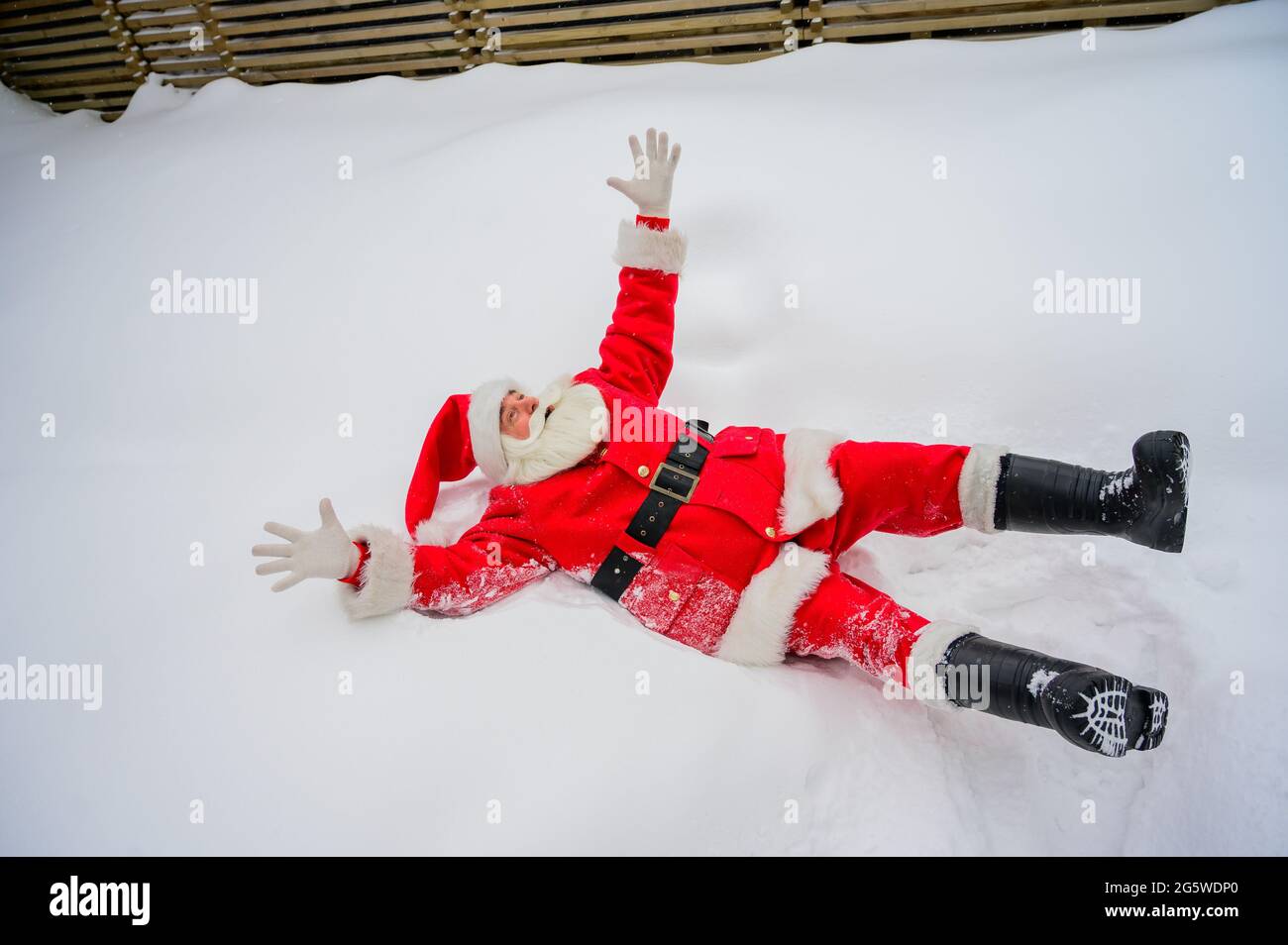 Happy santa claus lying in the snow and fooling around Stock Photo - Alamy