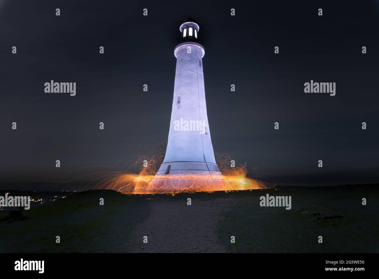 Fireworks and fire around the base of a lighthouse in the dead of night ...