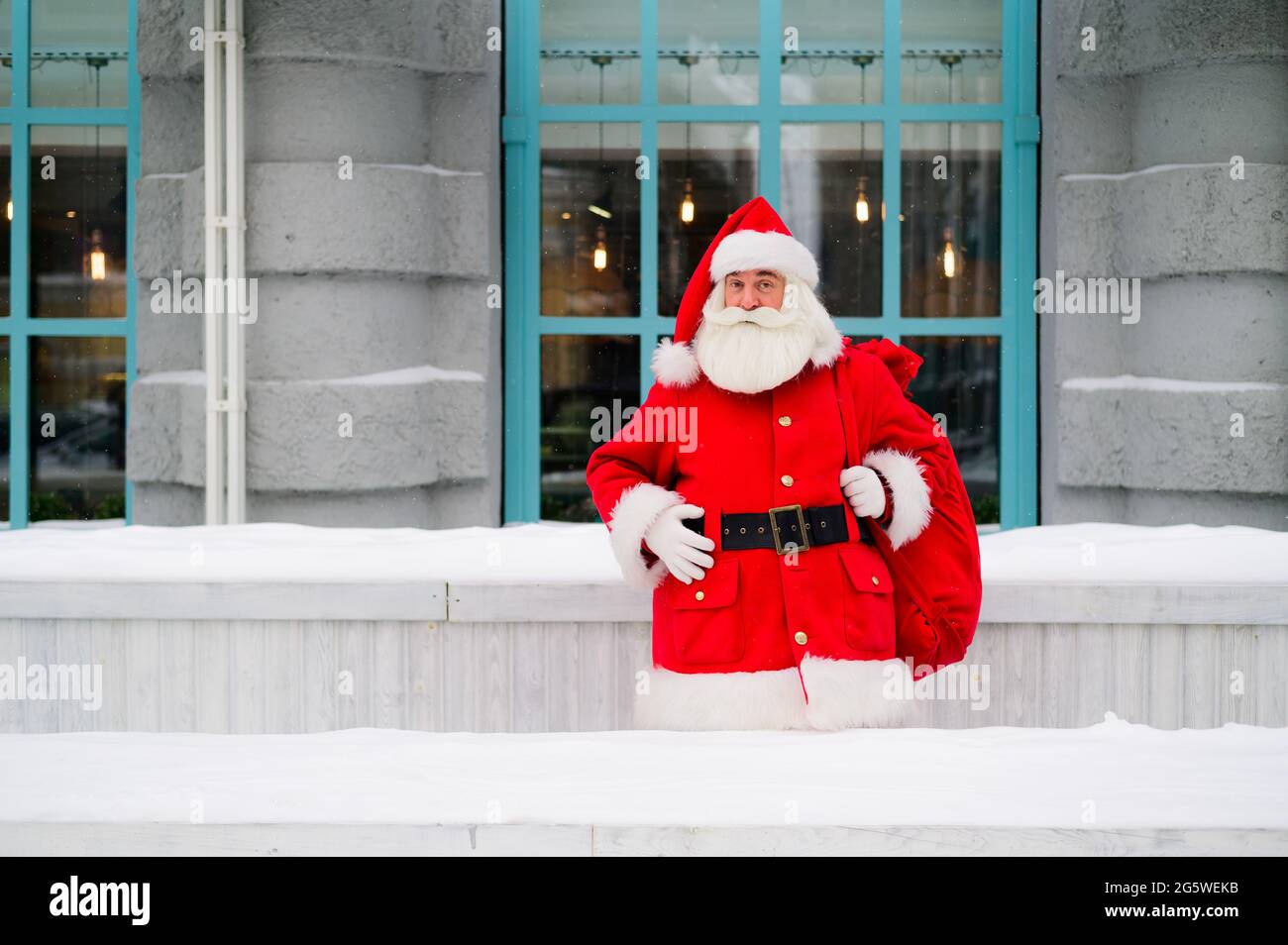 Pensive santa claus is leaning against the facade of a house in winter ...