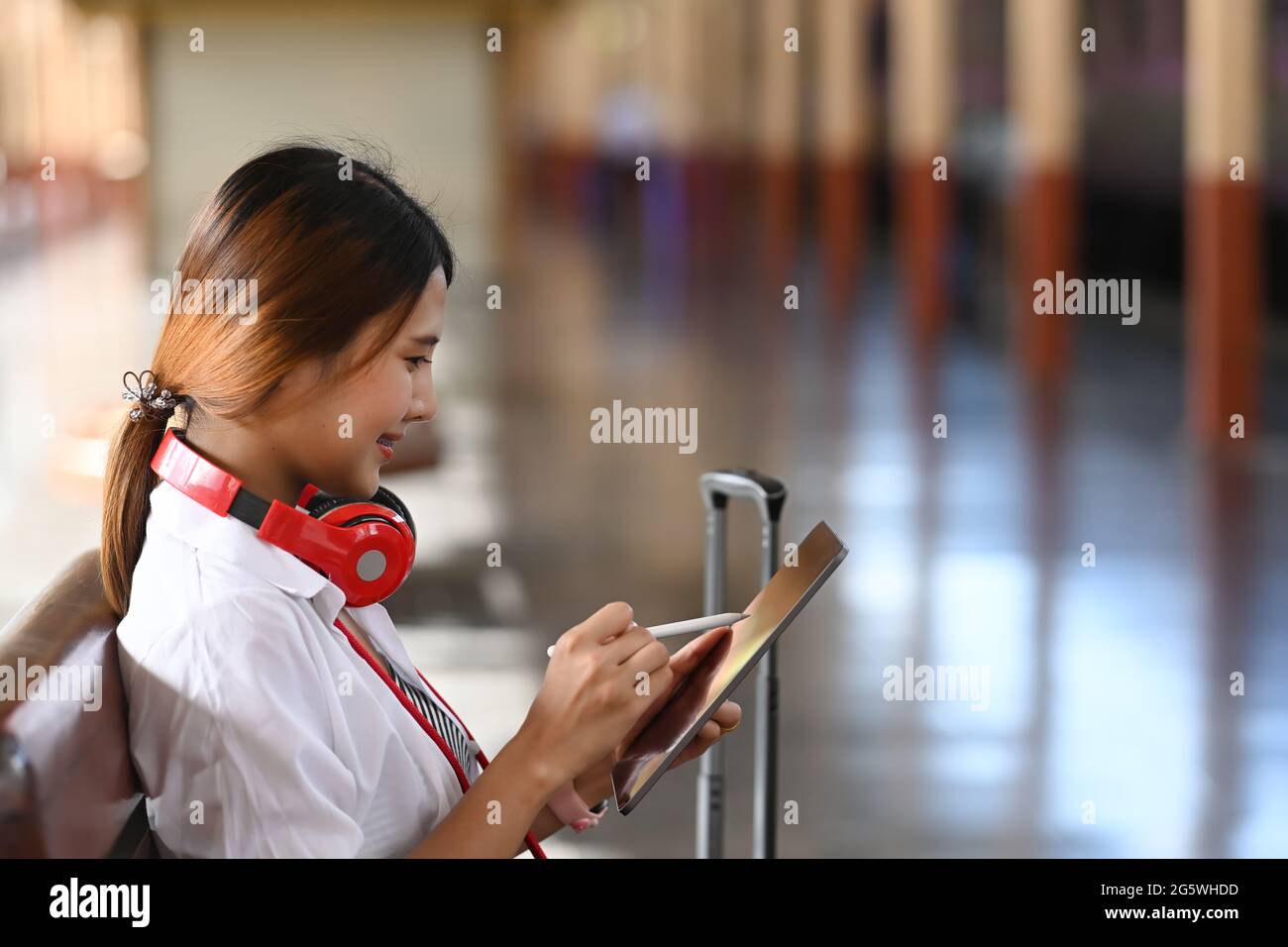 Happy Asian woman traveller using mobile phone and waiting for a bus at ...