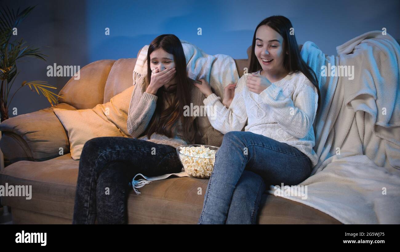Two girls laughing while watching comedy show on TV at night Stock ...
