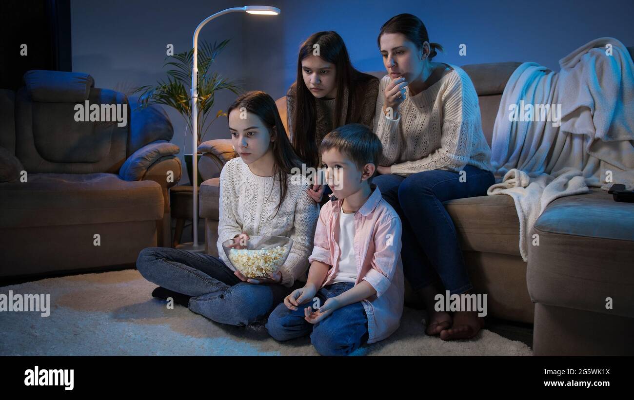 Family closing eyes and getting scared while watching horror movie or ...