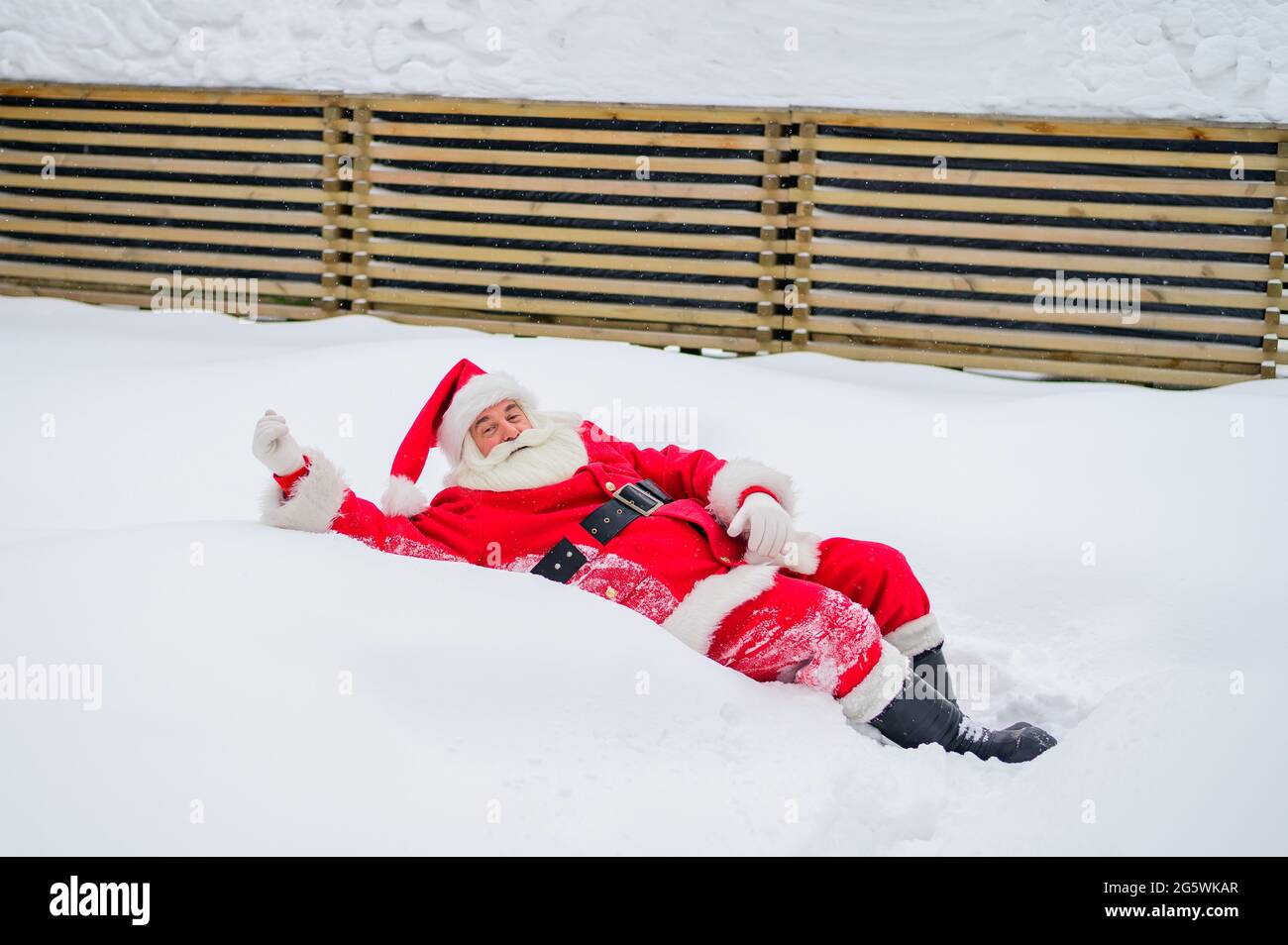 Happy santa claus lying in the snow and fooling around Stock Photo - Alamy