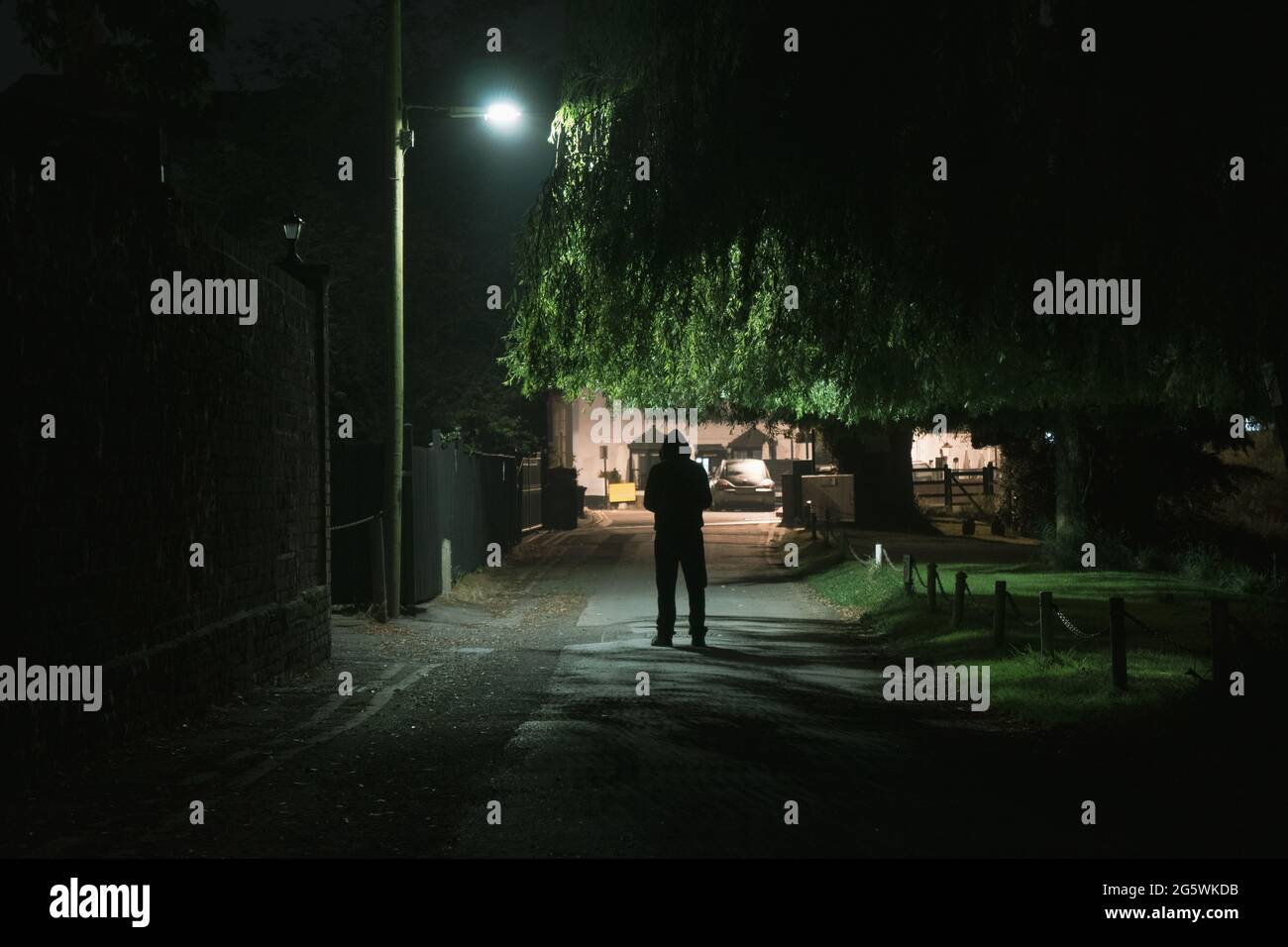 A mysterious hooded figure. Standing under a street light in a town. at ...