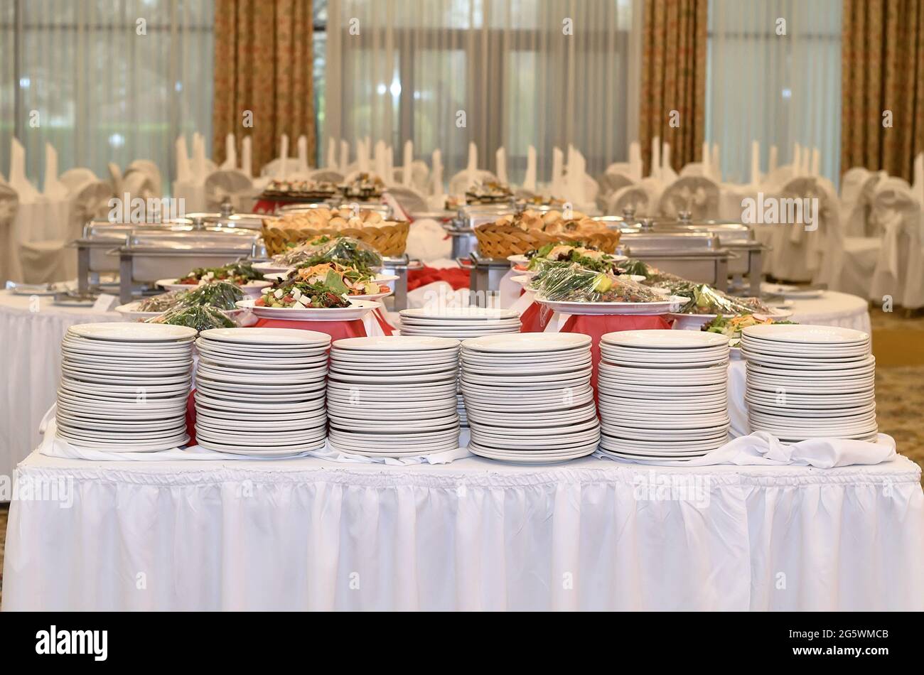 Catering table with a white tablecloth and six stacks where there are a ...