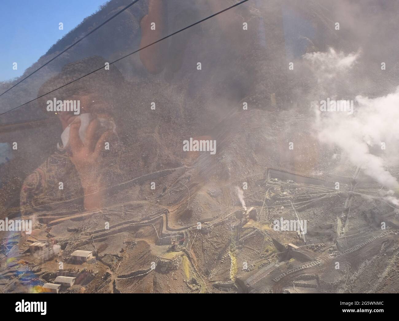 Mask wearing tourist on Hakone Ropeway traversing the sulphurous ...