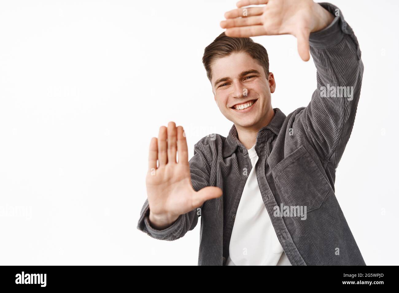 Portrait of attractive young man capture moment, looks through hand ...