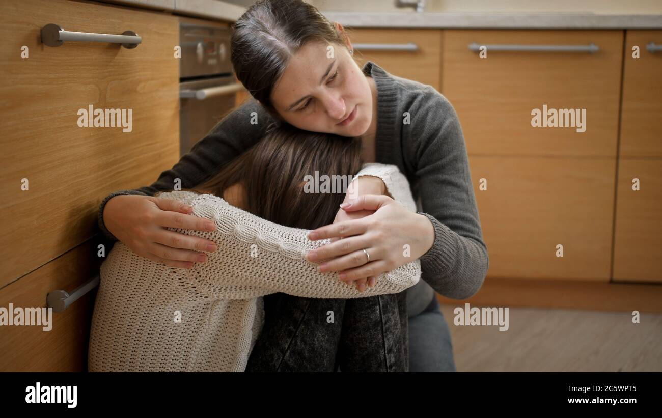 Upset crying teenage girl sitting on floor and hugging mother. Concept ...