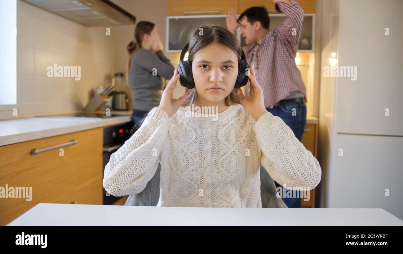 Teenage girl putting on headphones to close ears because of arguing and ...