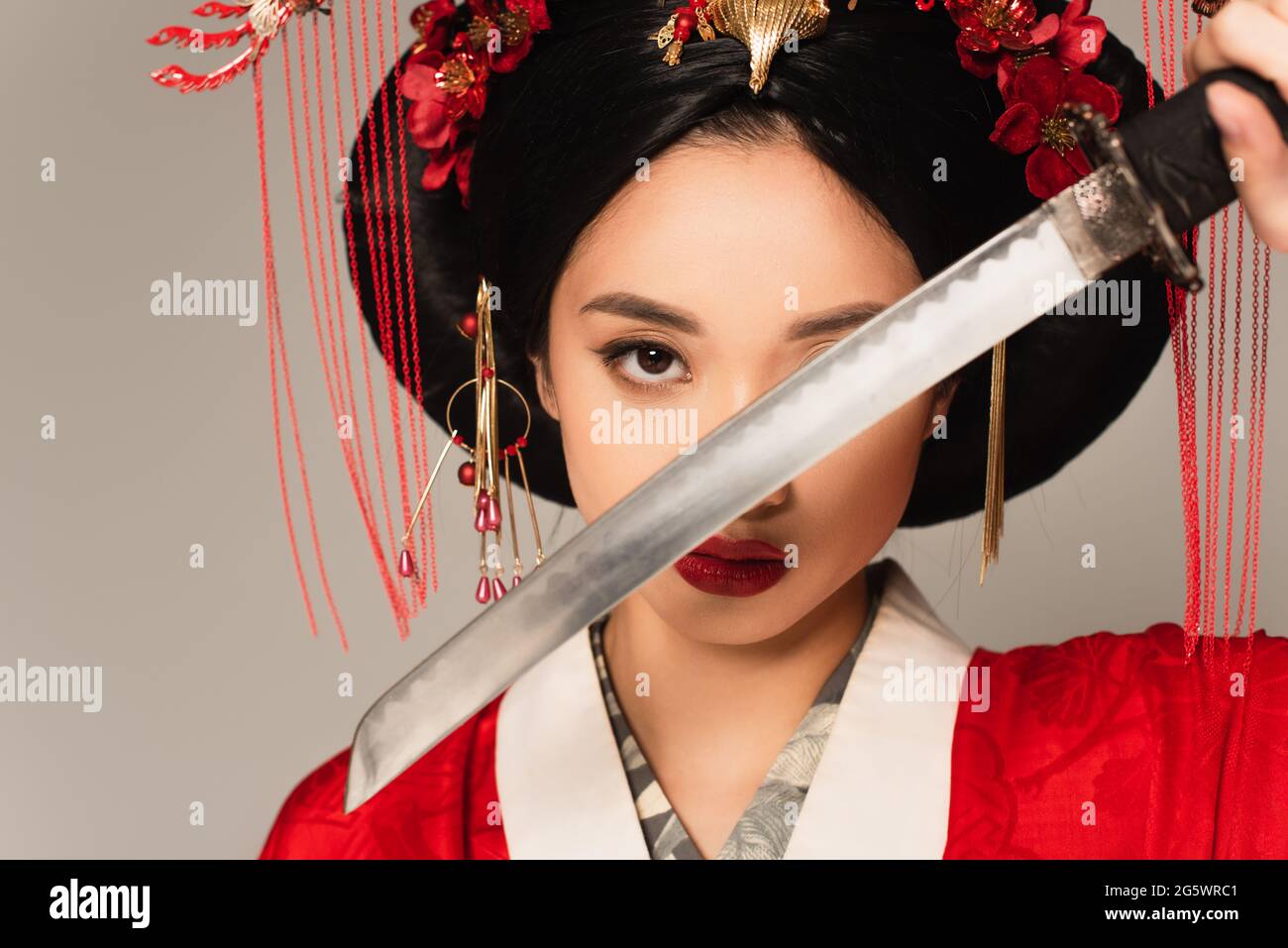 Japanese woman in national costume holding blurred sword near face ...