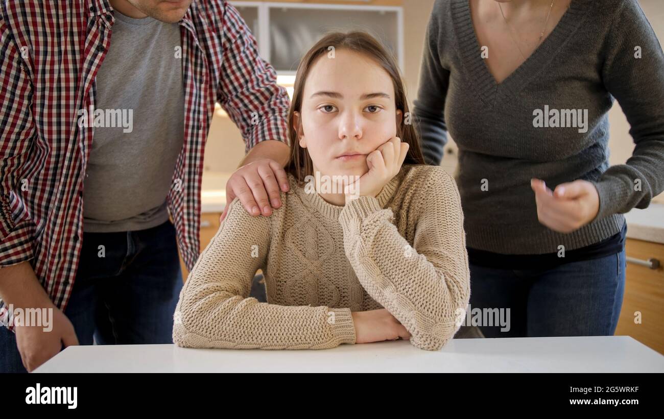 Teenage girl looking in camera and ignoring parents shouting at her ...