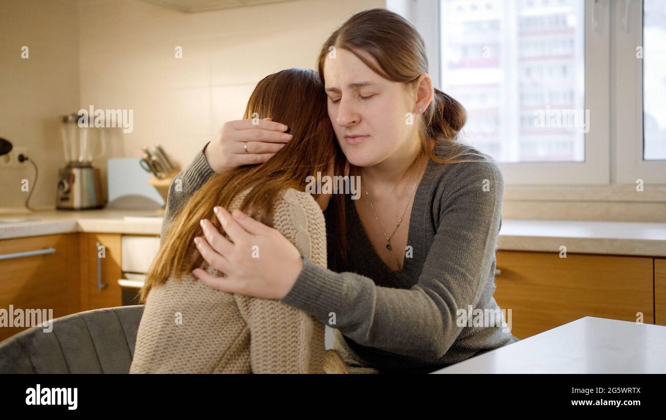 Young mother comforting and consoling her upset teenage daughter. Parent supporting and ...