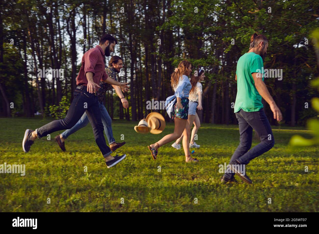 Group of happy young people running on grass in summer park. Youth on ...