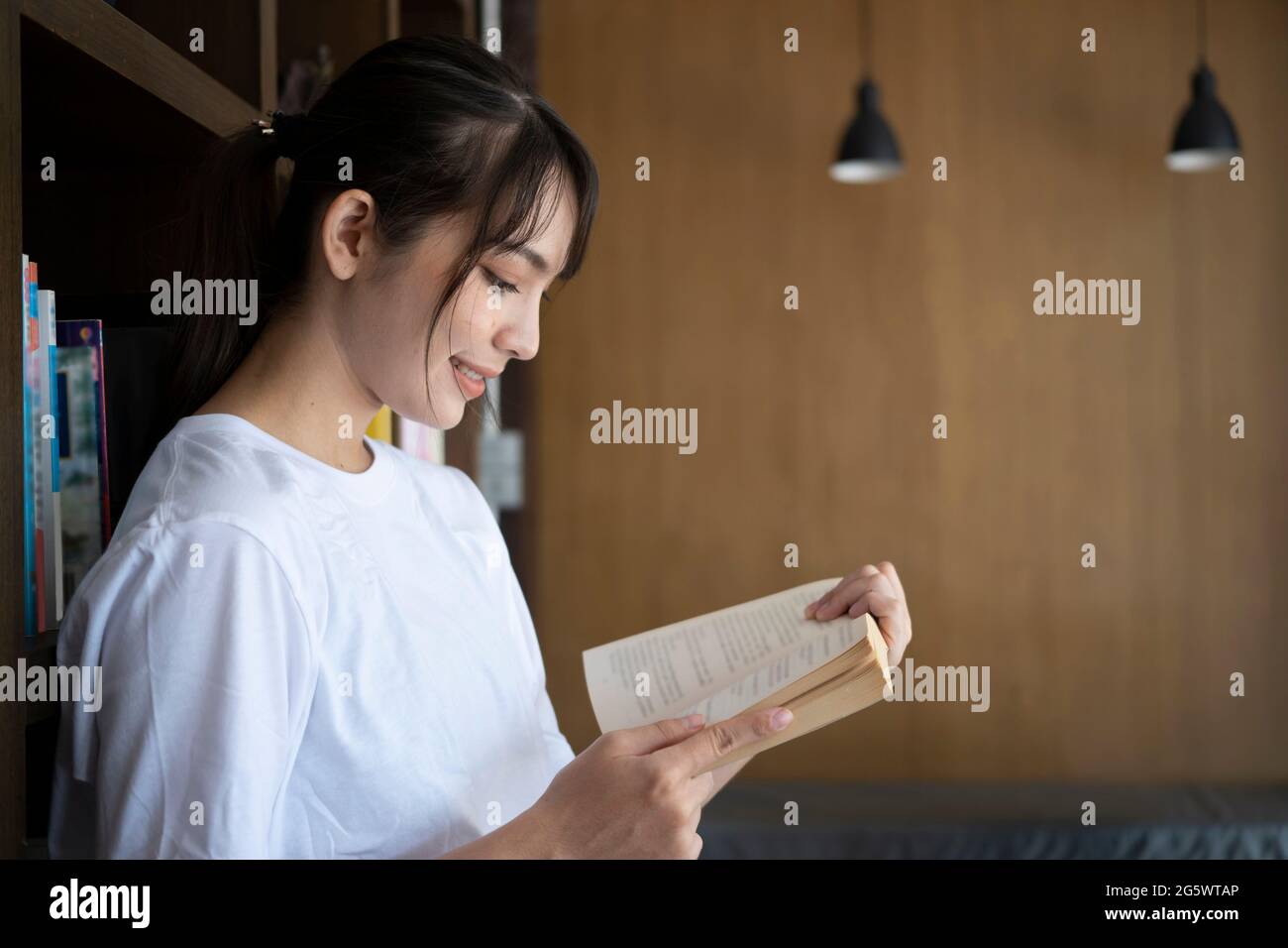 Young woman reading a book in library Stock Photo - Alamy