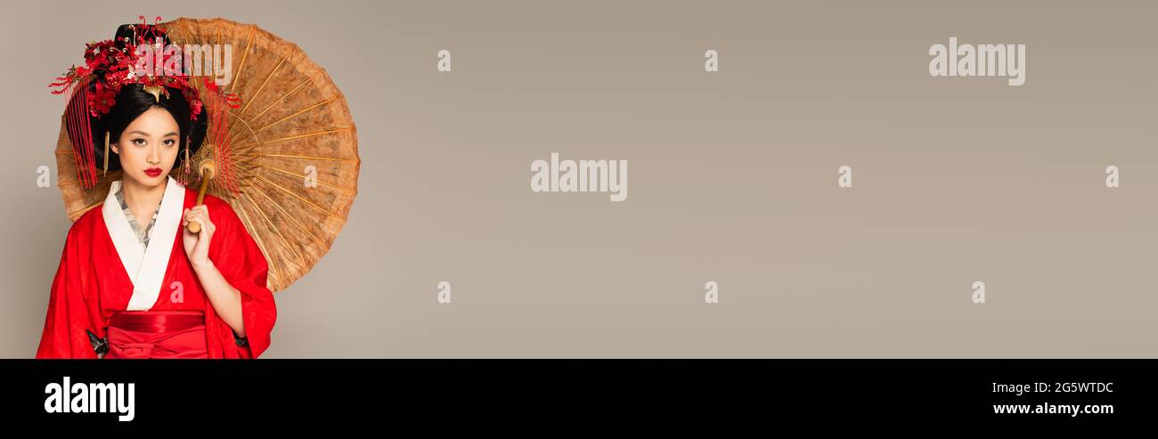 Young asian woman in national costume holding umbrella isolated on grey ...