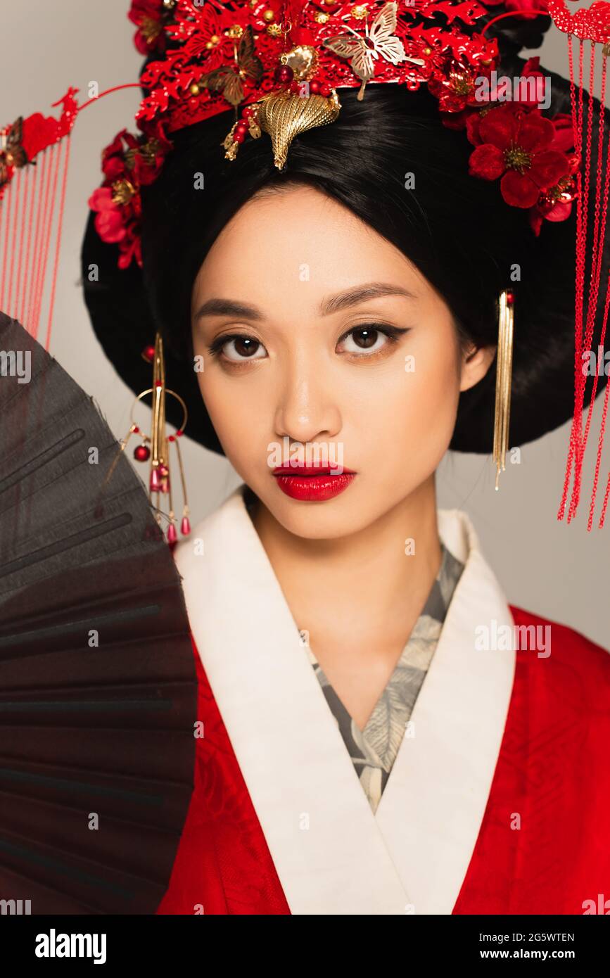 Asian woman with red lips holding black fan isolated on grey Stock ...