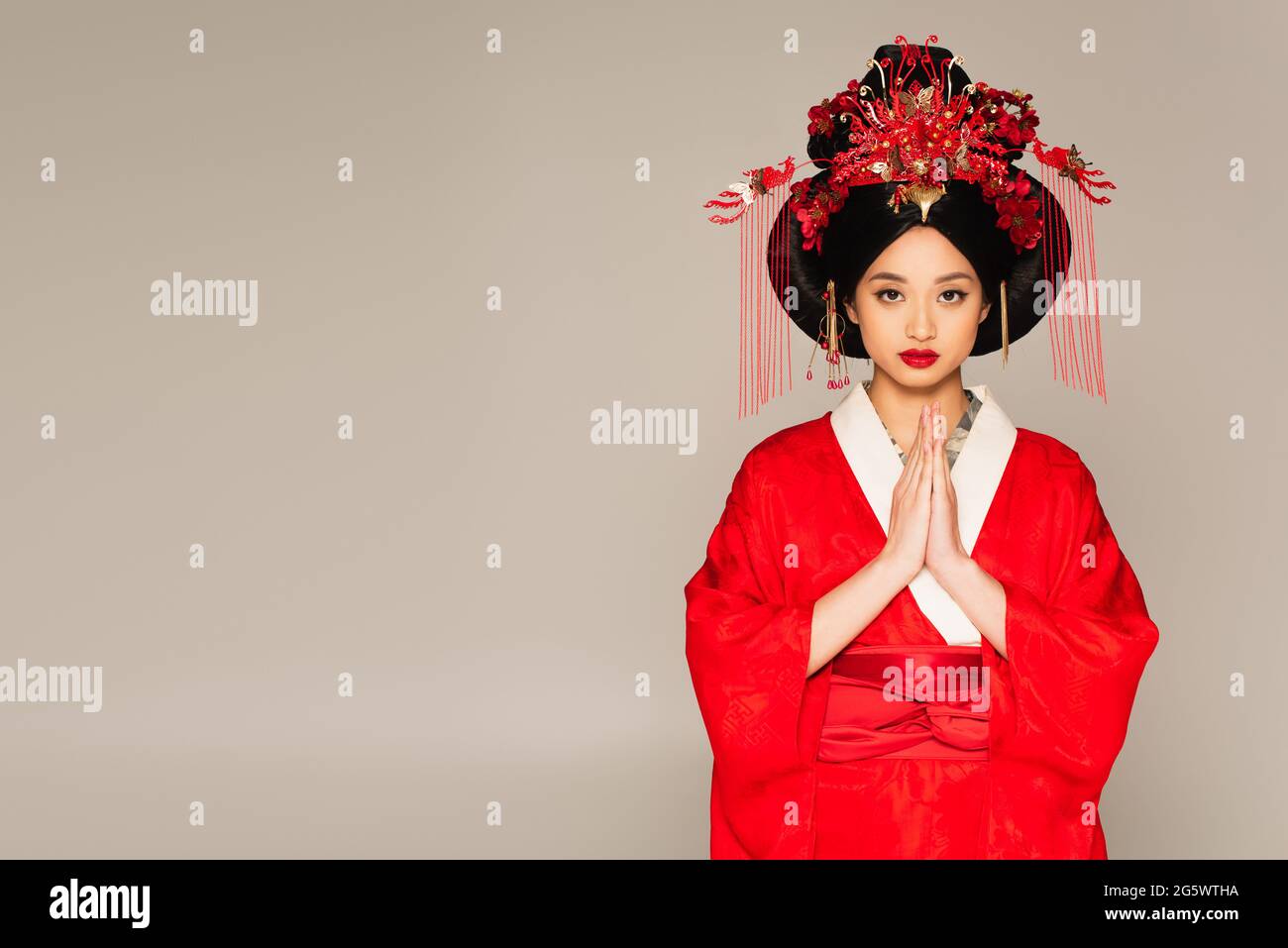 Asian woman with red lips showing praying hands isolated on grey Stock ...