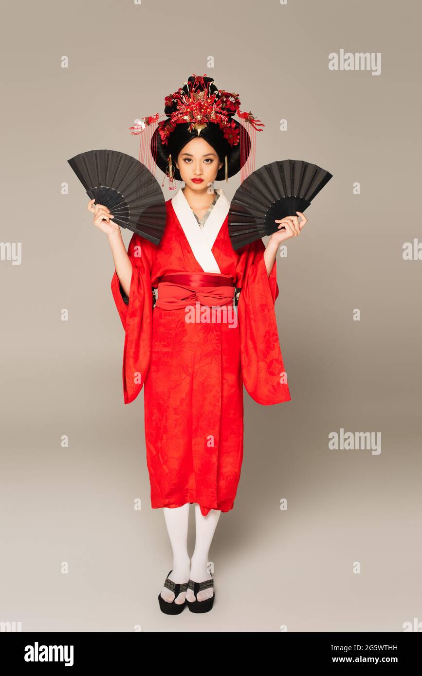Asian woman in traditional clothes holding black fans on grey ...